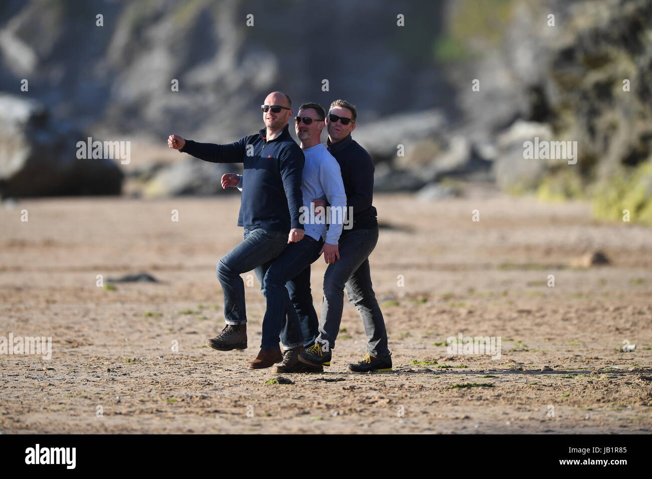 Three men walking and dancing in tandem on the beach Stock Photo - Alamy