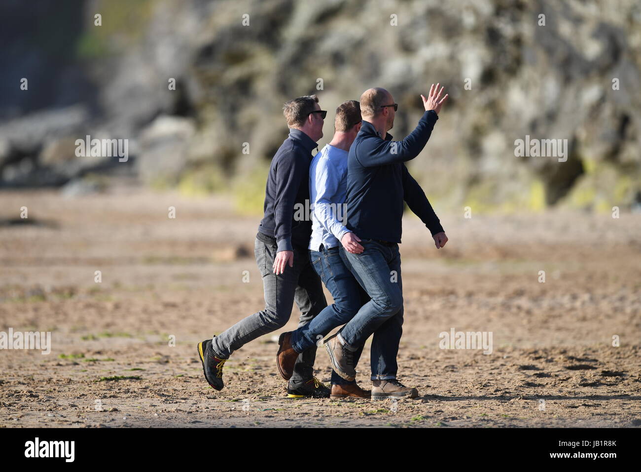 Three men walking and dancing in tandem on the beach Stock Photo - Alamy