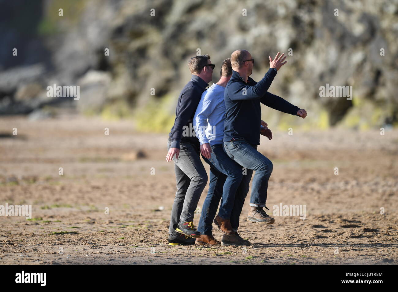 Three men walking and dancing in tandem on the beach Stock Photo - Alamy