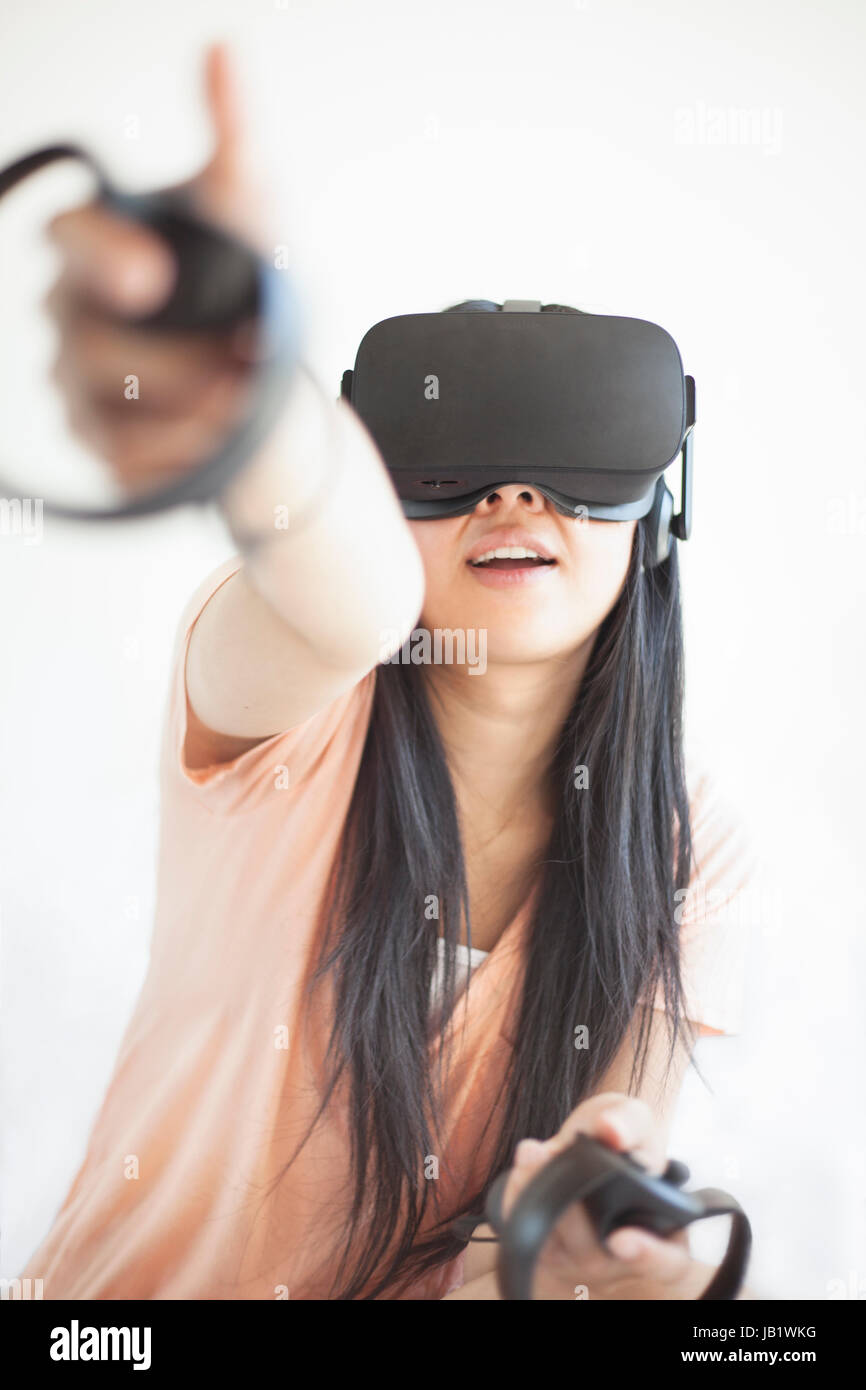 Young Asian woman wearing virtual reality headset Oculus Rift and ...
