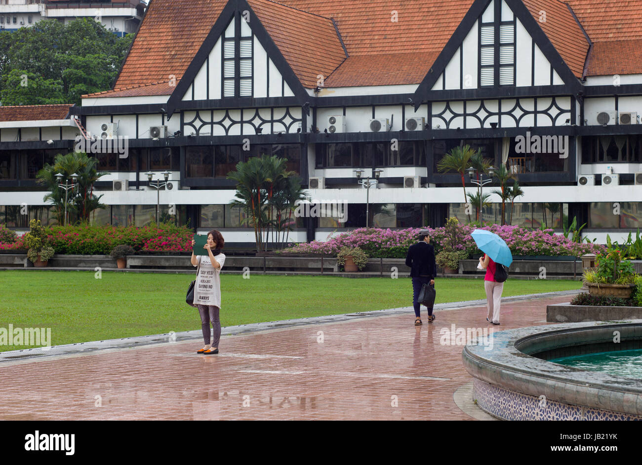 Female Asian tourist taking selfie in front of building on rainy day ...