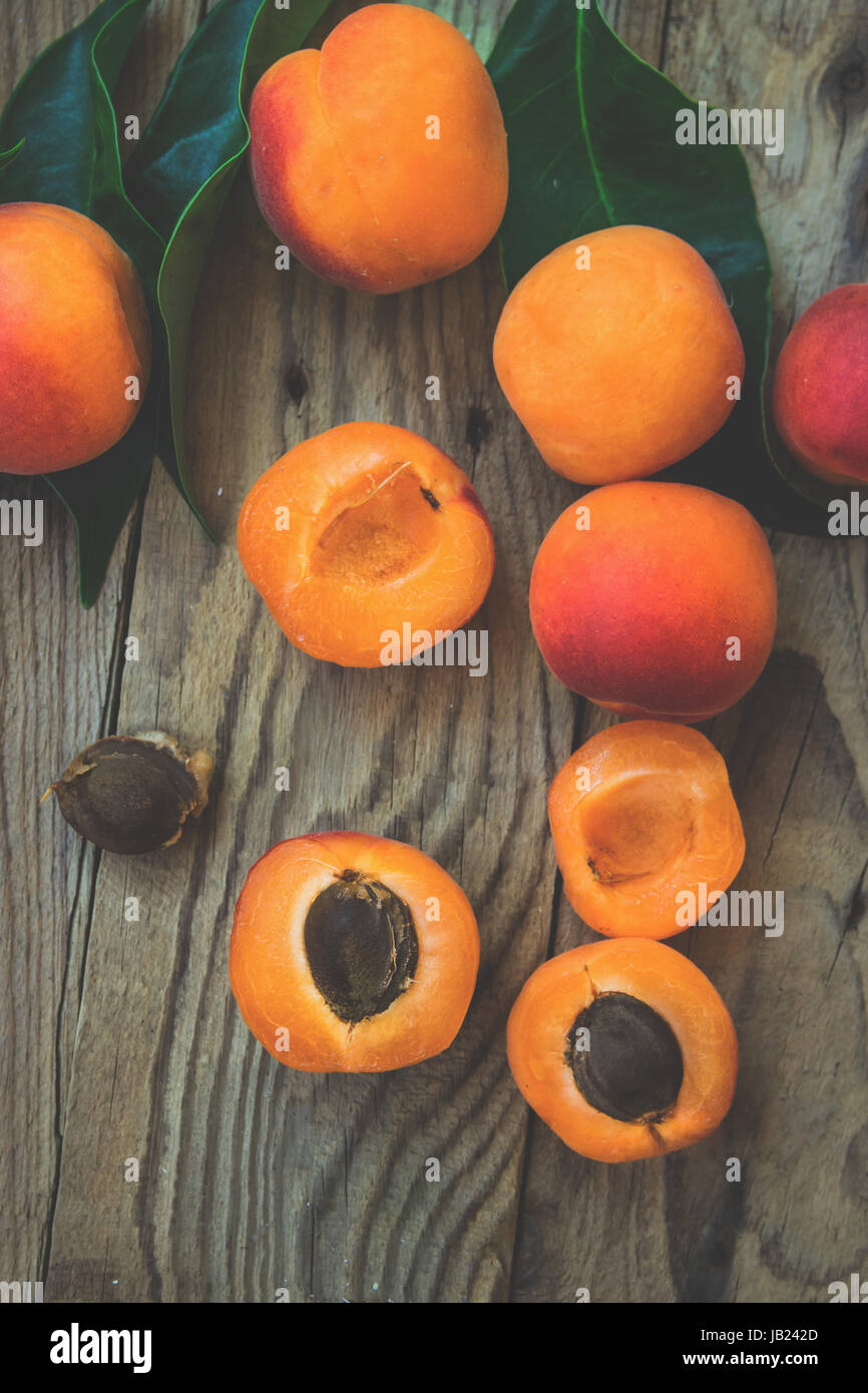 Fresh ripe colorful apricots halved and whole on weathered plank wood ...