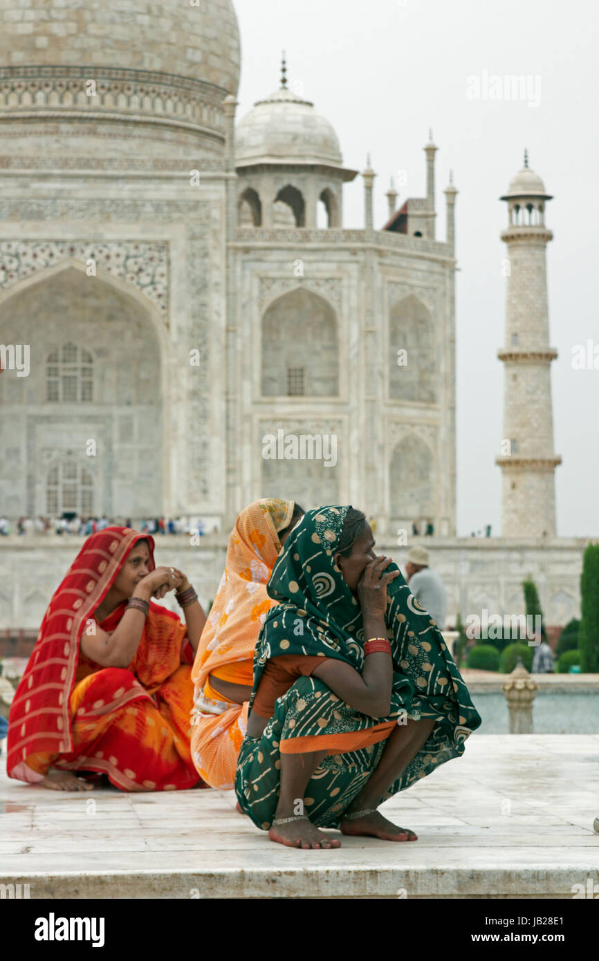 Group of Indian ladies in colorful sari's squatting on a white marble ...
