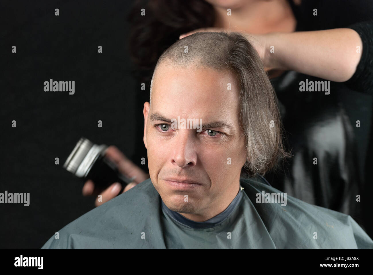 Close-up of a mourning man getting his long hair is shaved off for a ...