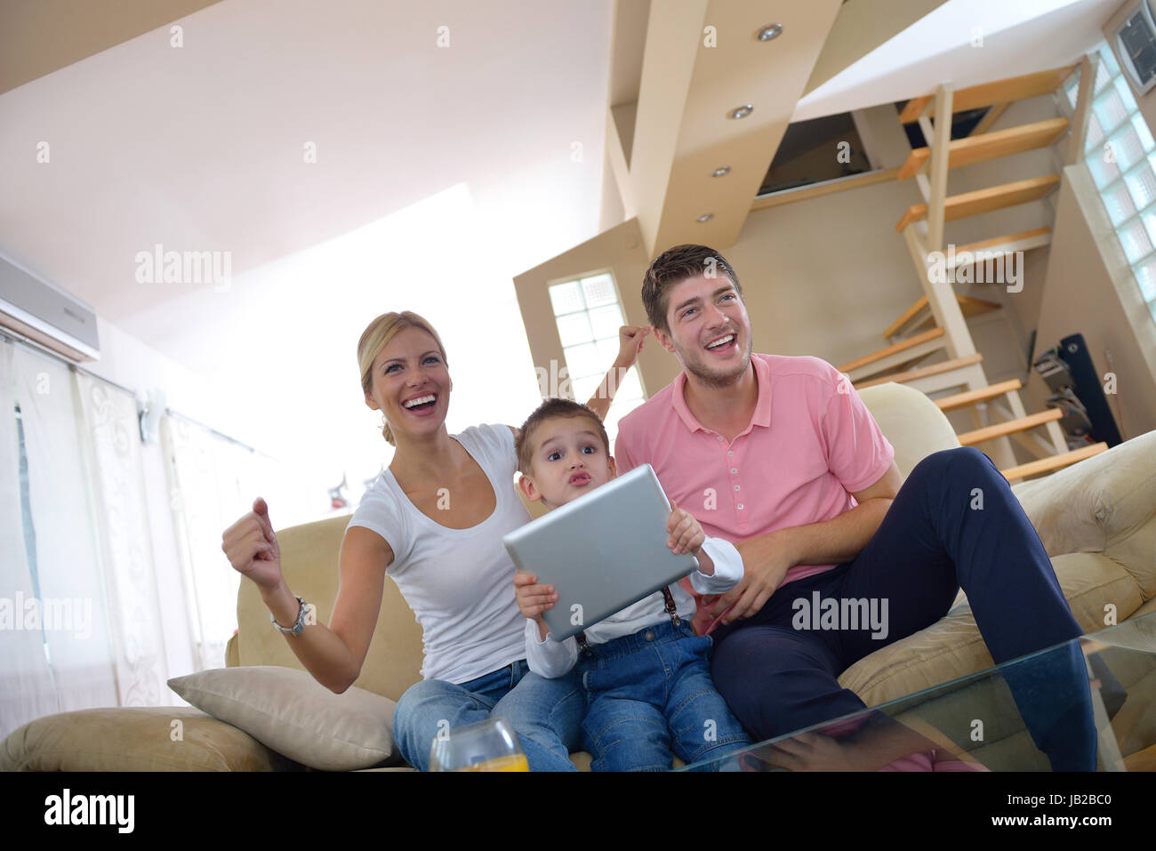 happy young family using tablet computer at modern home for playing ...