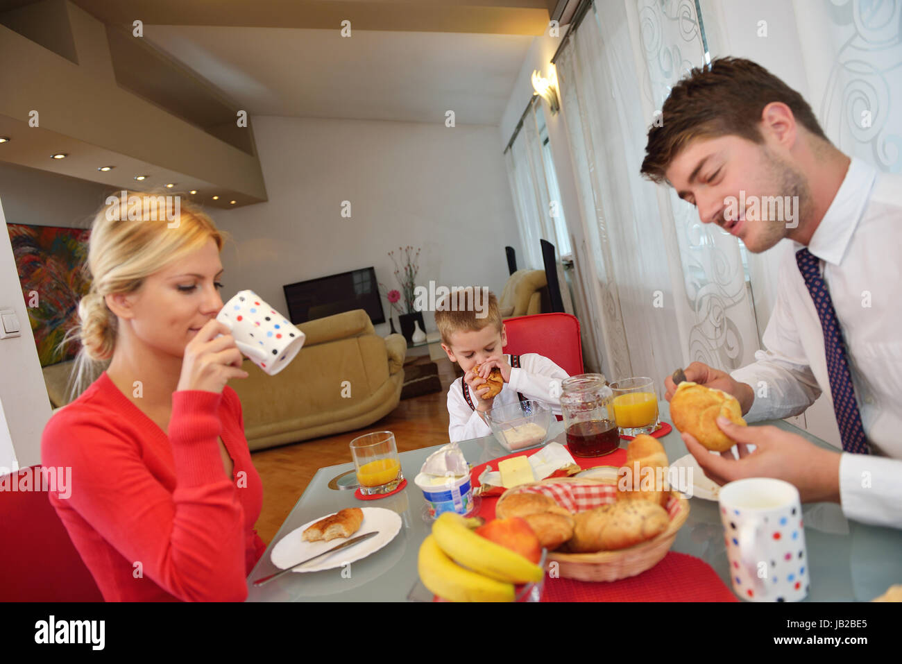 happy young family have healthy breakfast at kitchen with red details ...