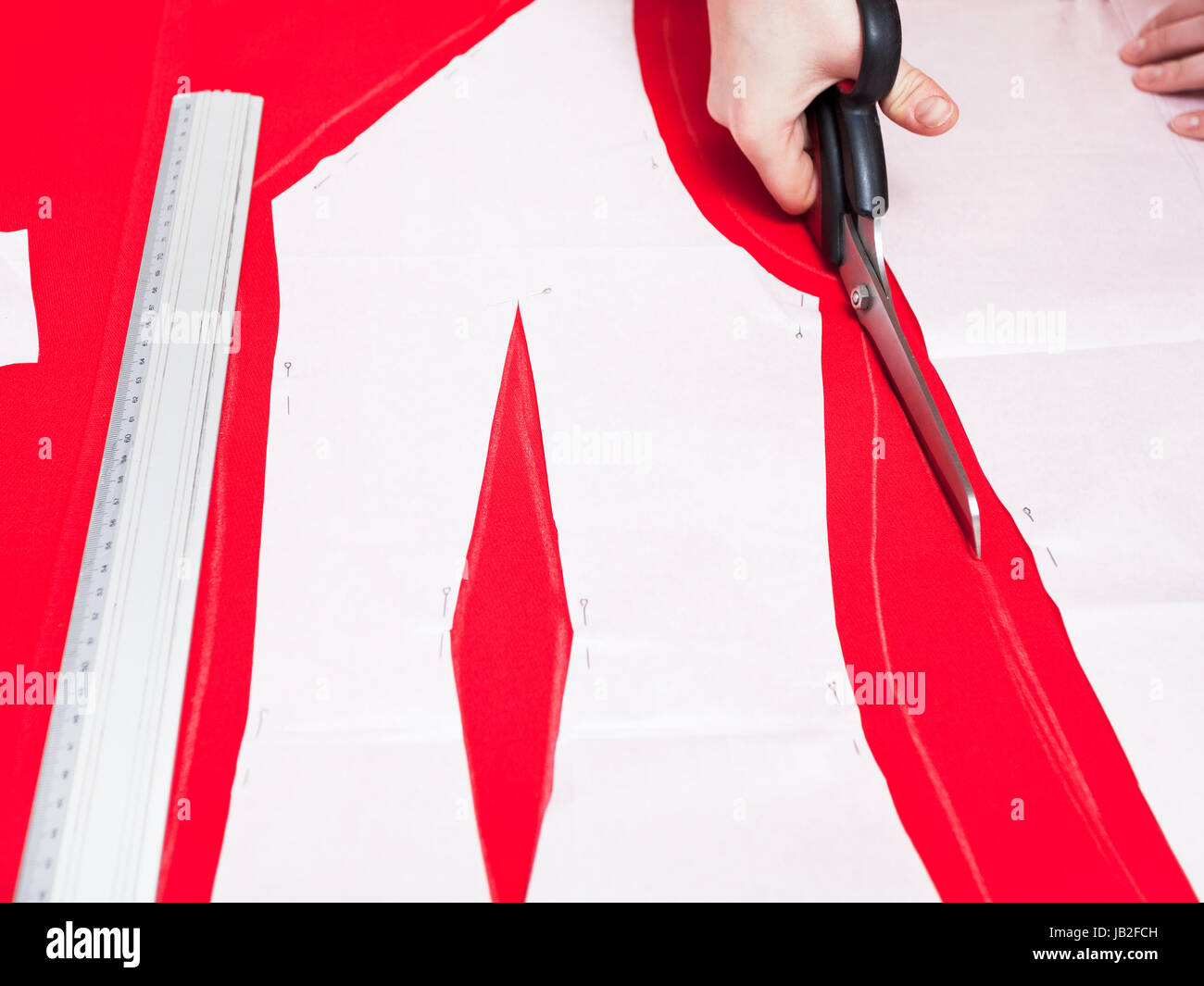 tailor cut out woolen fabric along pattern lines for tailoring red ...
