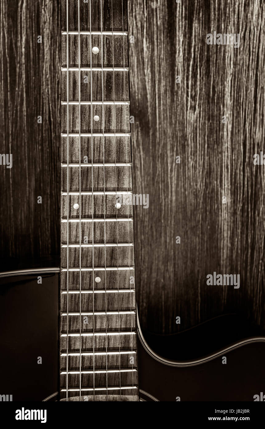 Detail of acoustic guitar in vintage style on wood texture background ...