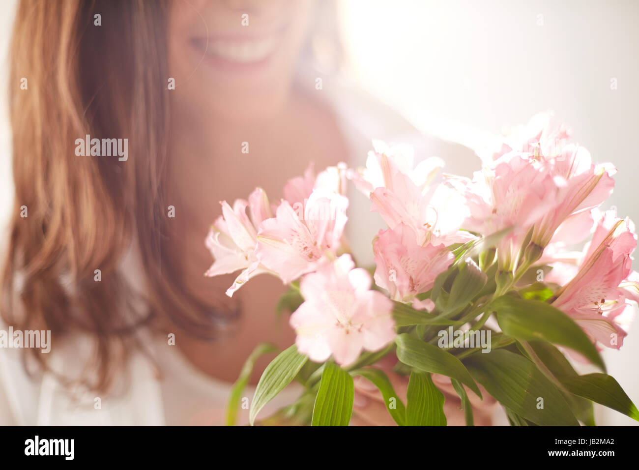 Close-up of smiling female holding bunch of pink lilies Stock Photo - Alamy