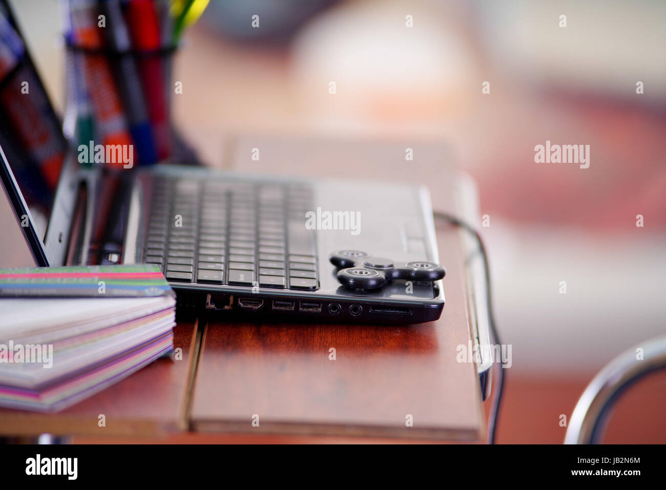 A popular fidget spinner toy over the laptop, on office background ...