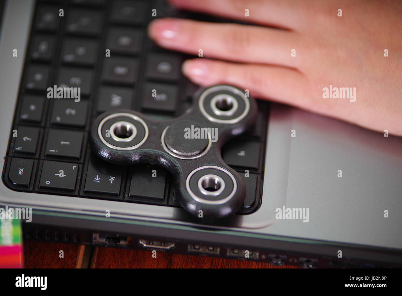 Young woman working in the computer and a popular fidget spinner toy ...