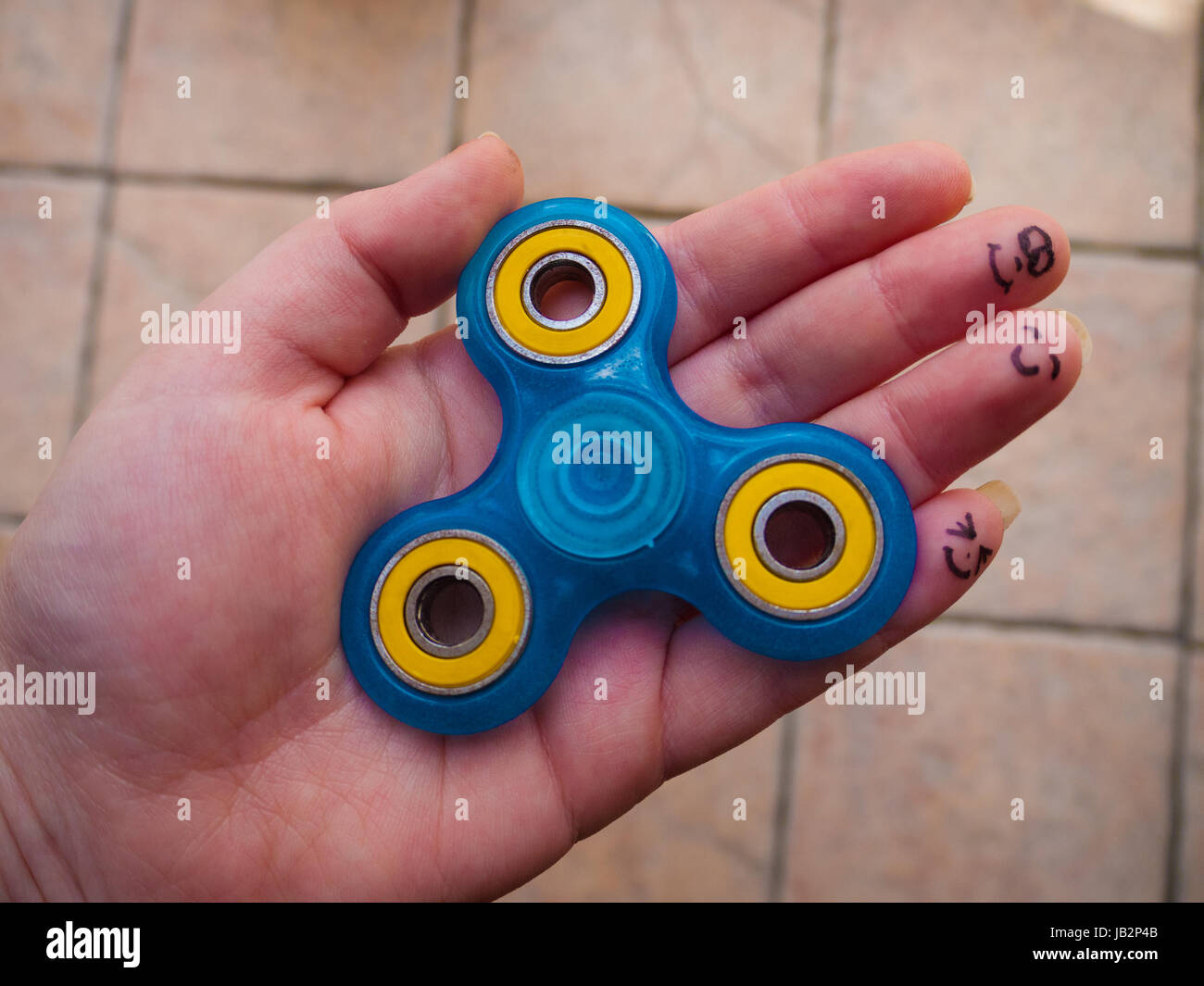 A motionless fidget spinner in a hand with smiling faces on the last ...