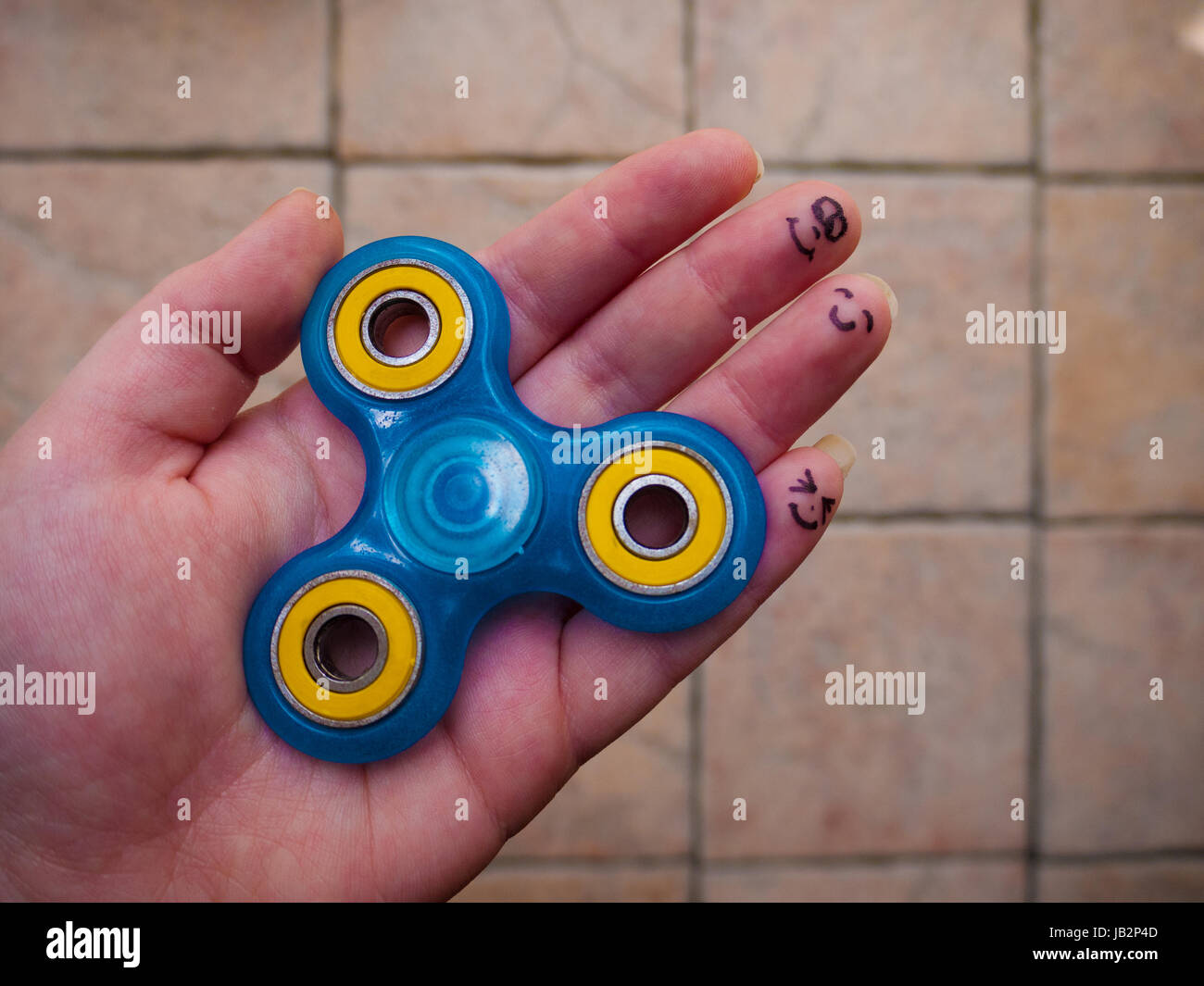 A motionless fidget spinner in a hand with smiling faces on the last ...