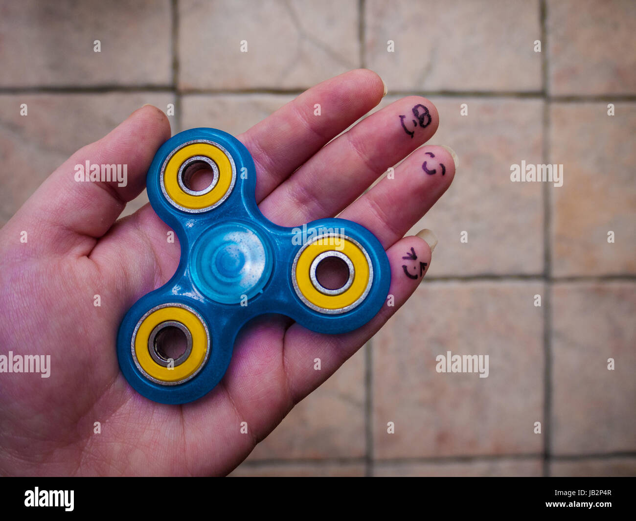 A motionless fidget spinner in a hand with smiling faces on the last ...