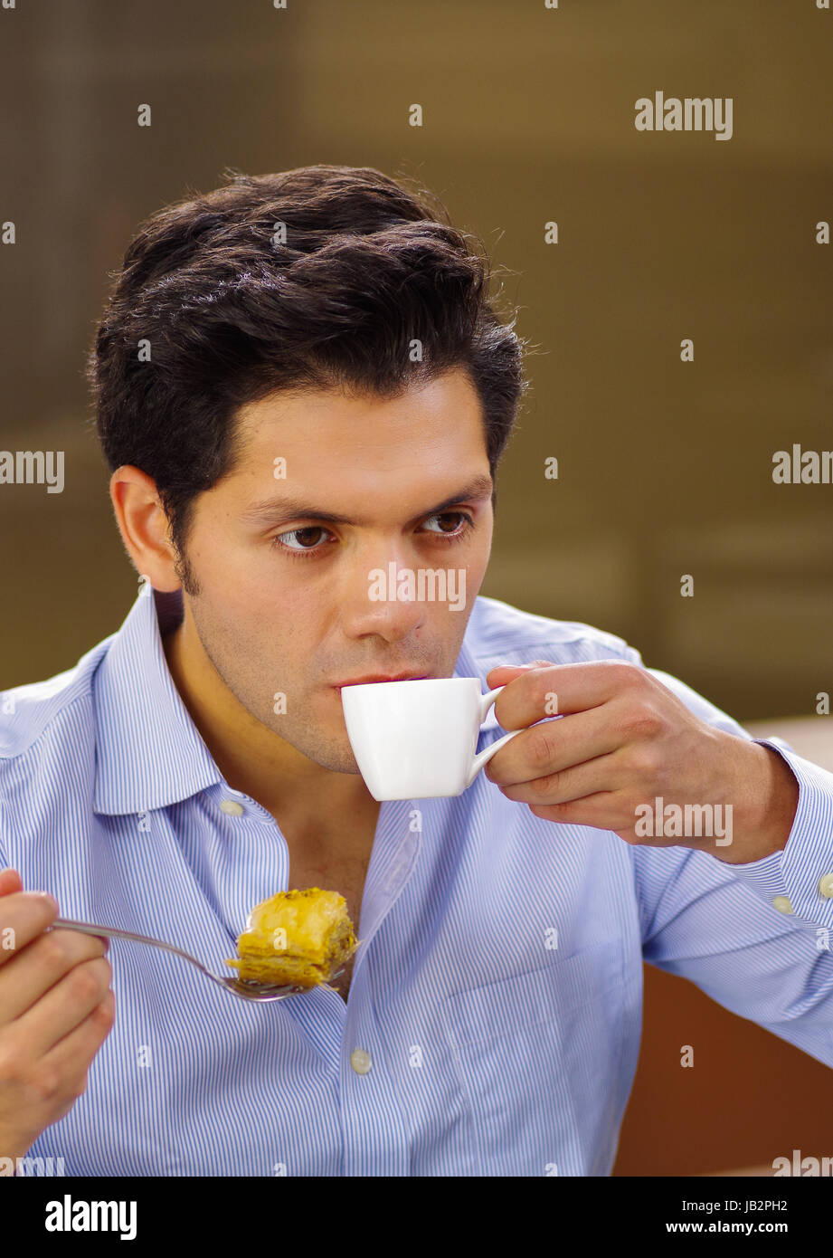 Handsome man drinking a cup of coffe and eating a delicious traditional ...