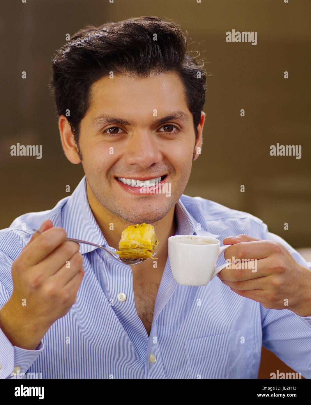 Handsome man drinking a cup of coffe and eating a delicious traditional ...