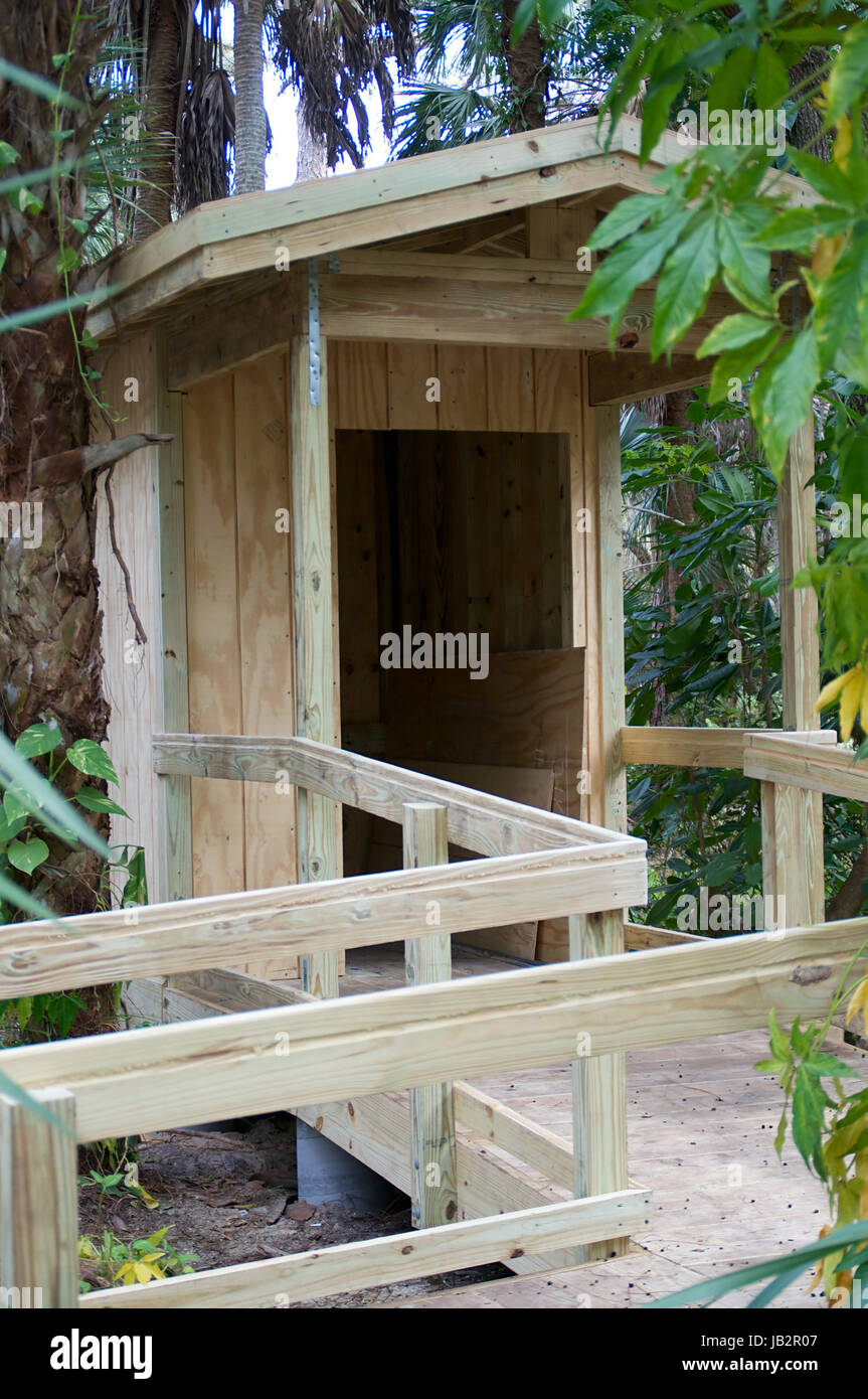 An almost completed shed made of wood with a ramp surrounded by trees ...