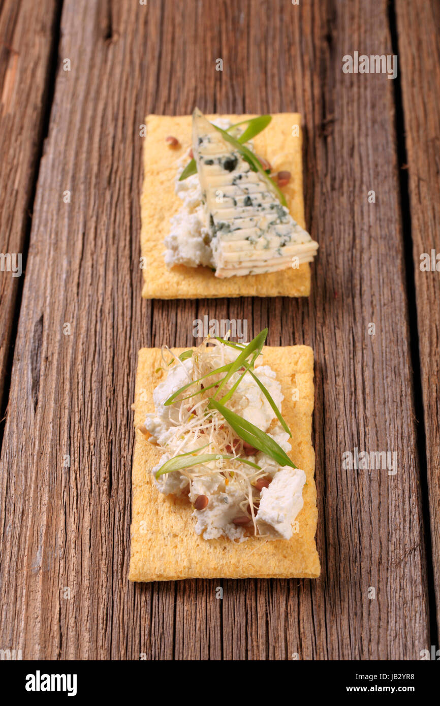 Two slices of corn crispbread with cheese toppings Stock Photo - Alamy