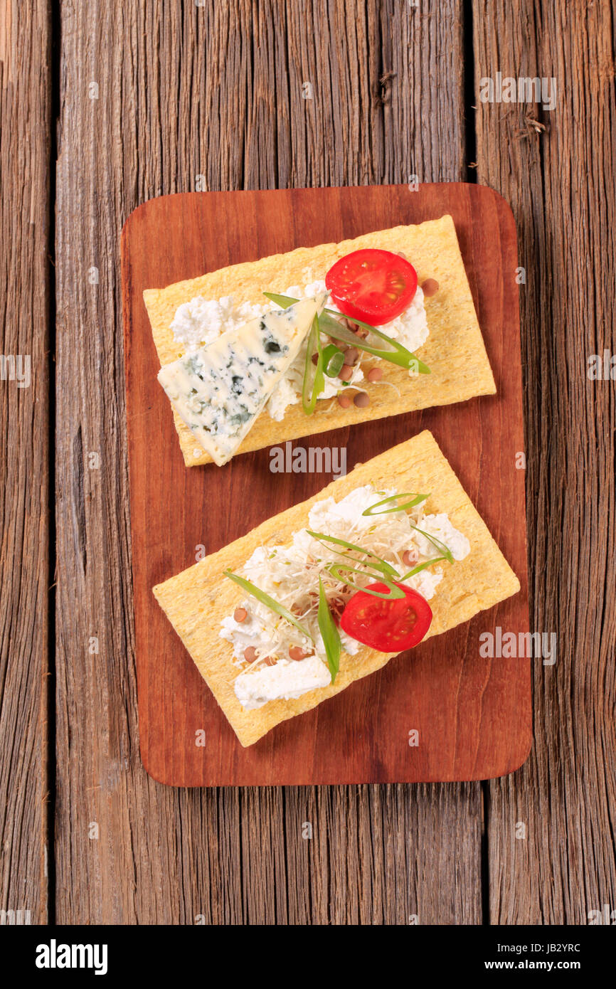 Two slices of corn crispbread with cheese toppings Stock Photo - Alamy