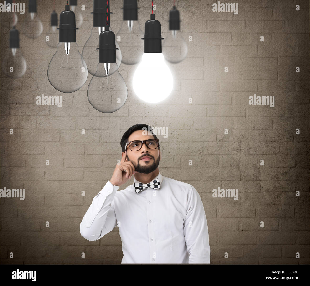 Thoughtful businessman looking at light bulb Stock Photo - Alamy