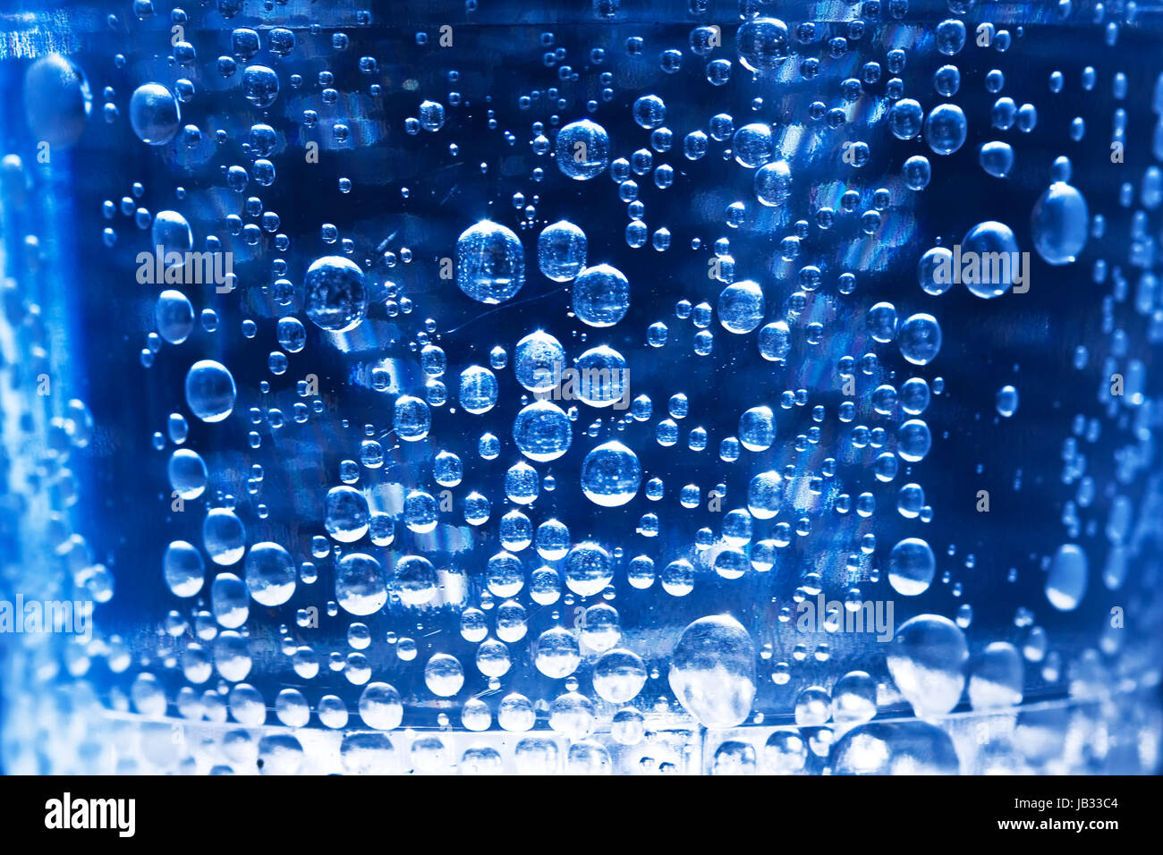 Bubbles in glass of water on a blue background Stock Photo - Alamy