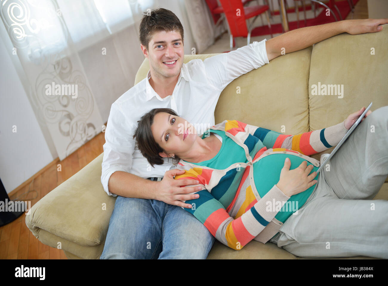pregnant woman with her husband have fun relax and using tablet comture ...