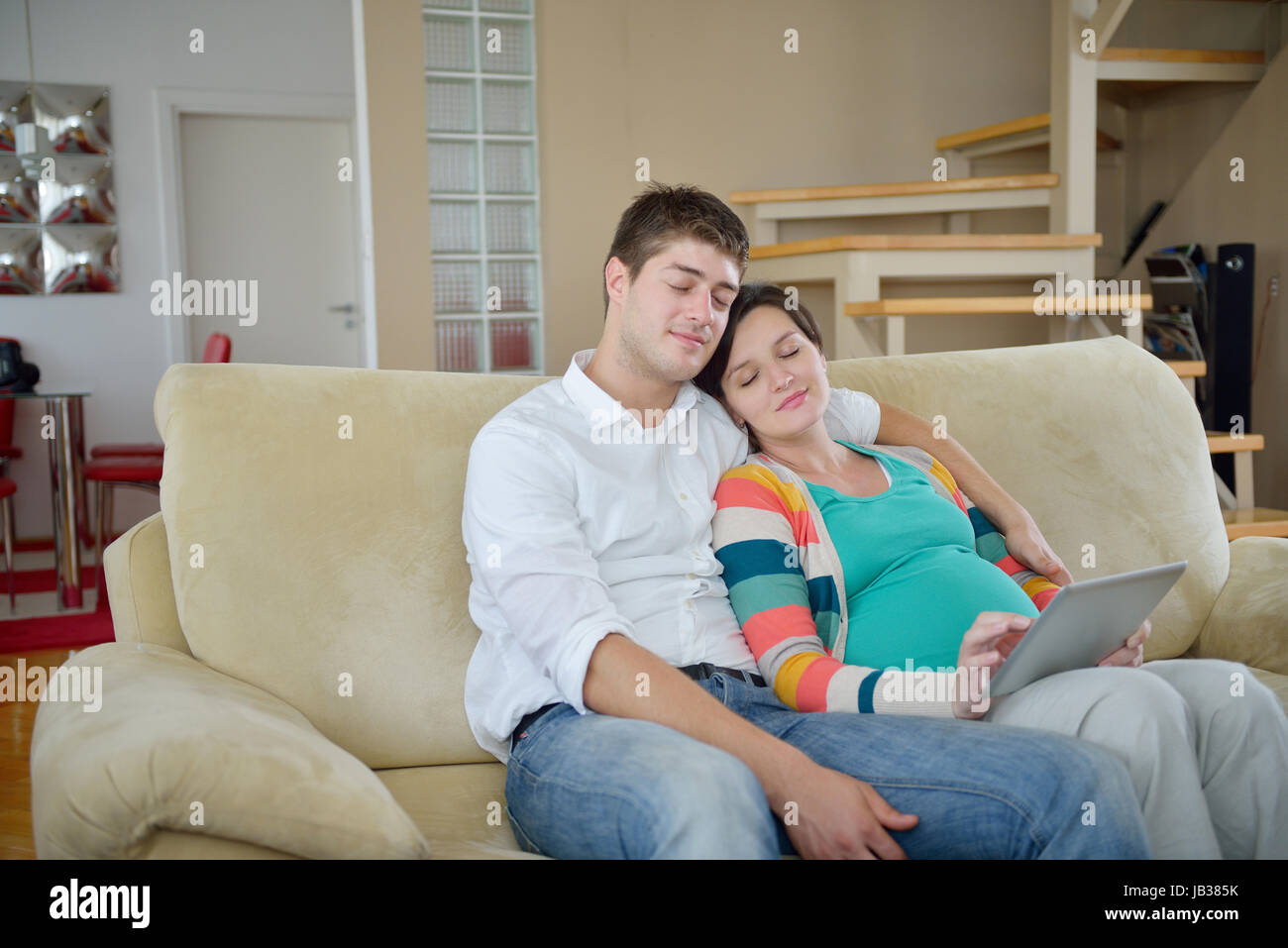 pregnant woman with her husband have fun relax and using tablet comture ...