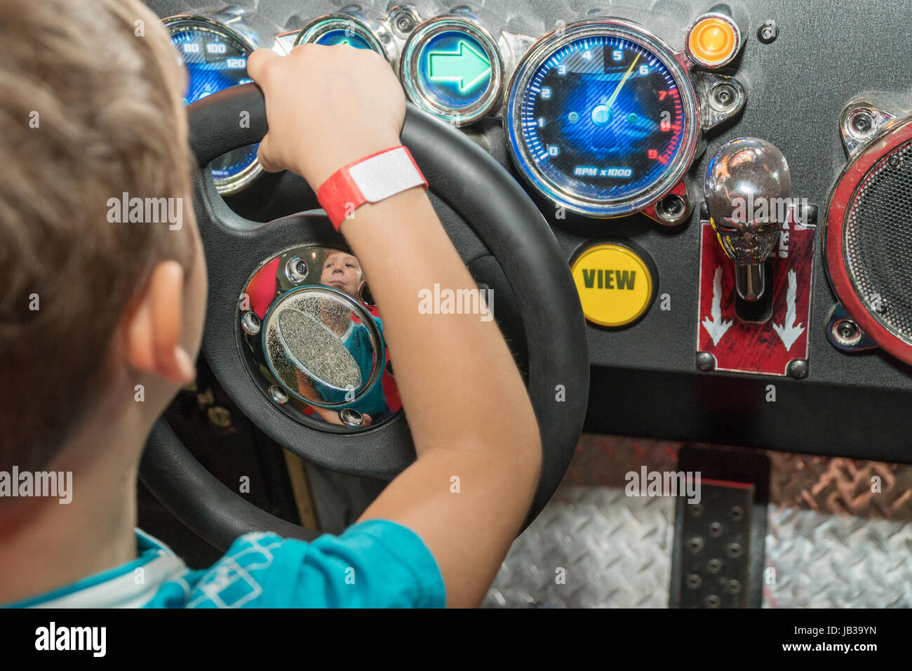 Little boy at the wheel of the car simulator with his back to the ...