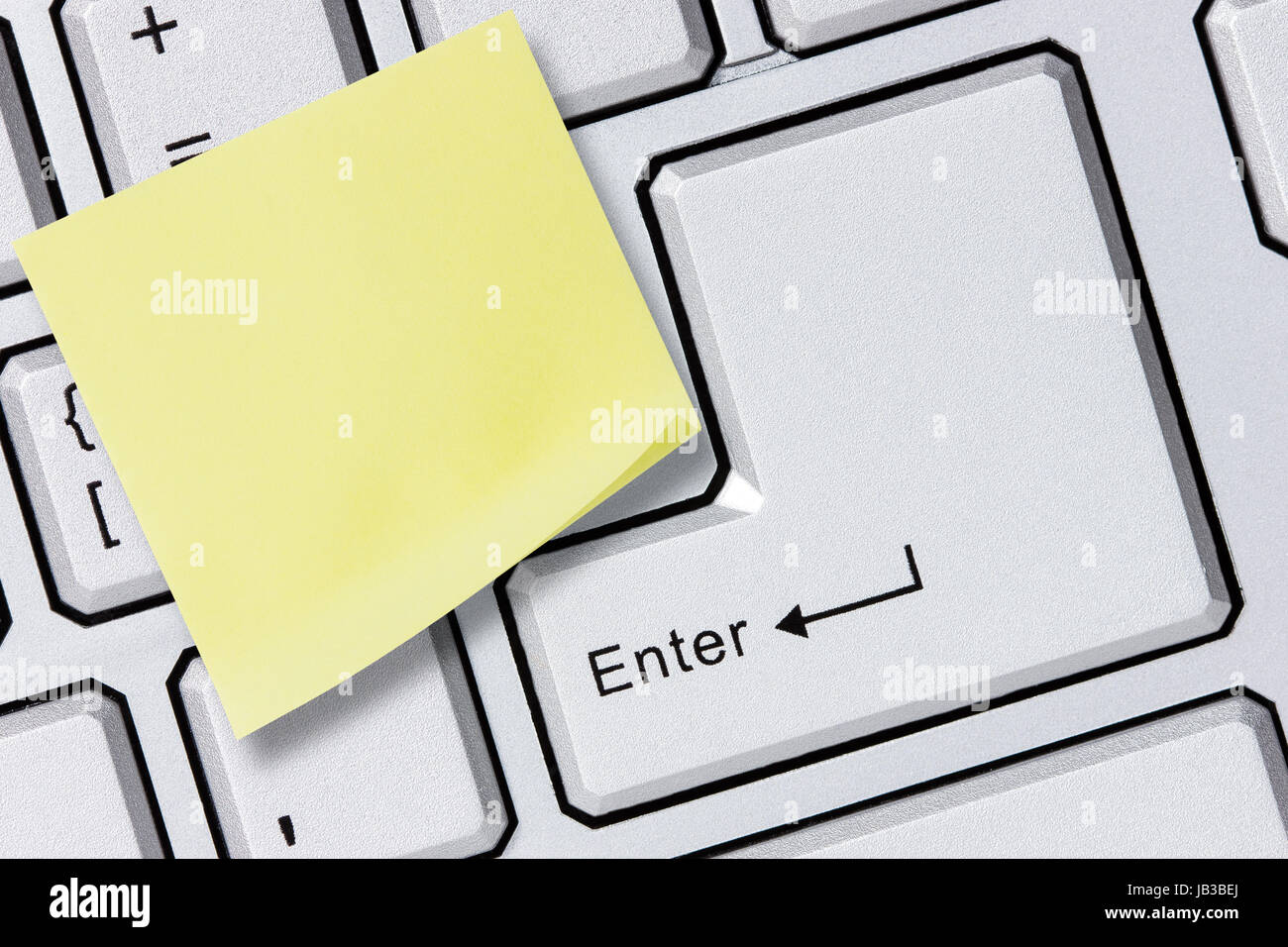 Silver computer keyboard with yellow reminder note Stock Photo - Alamy
