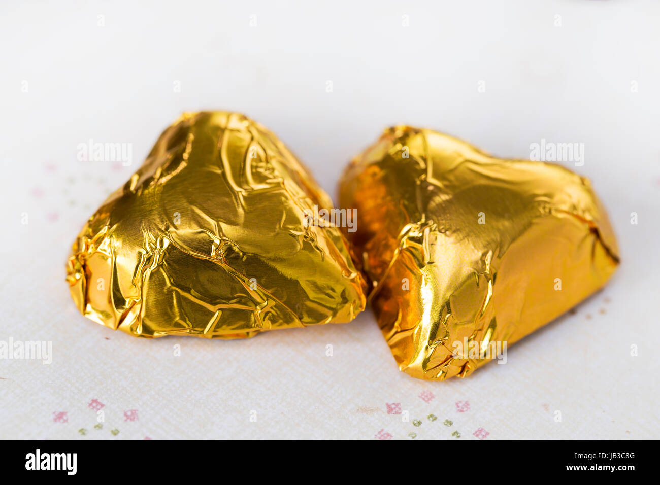 Chocolate candy hearts wrapped in gold foil, close up Stock Photo - Alamy