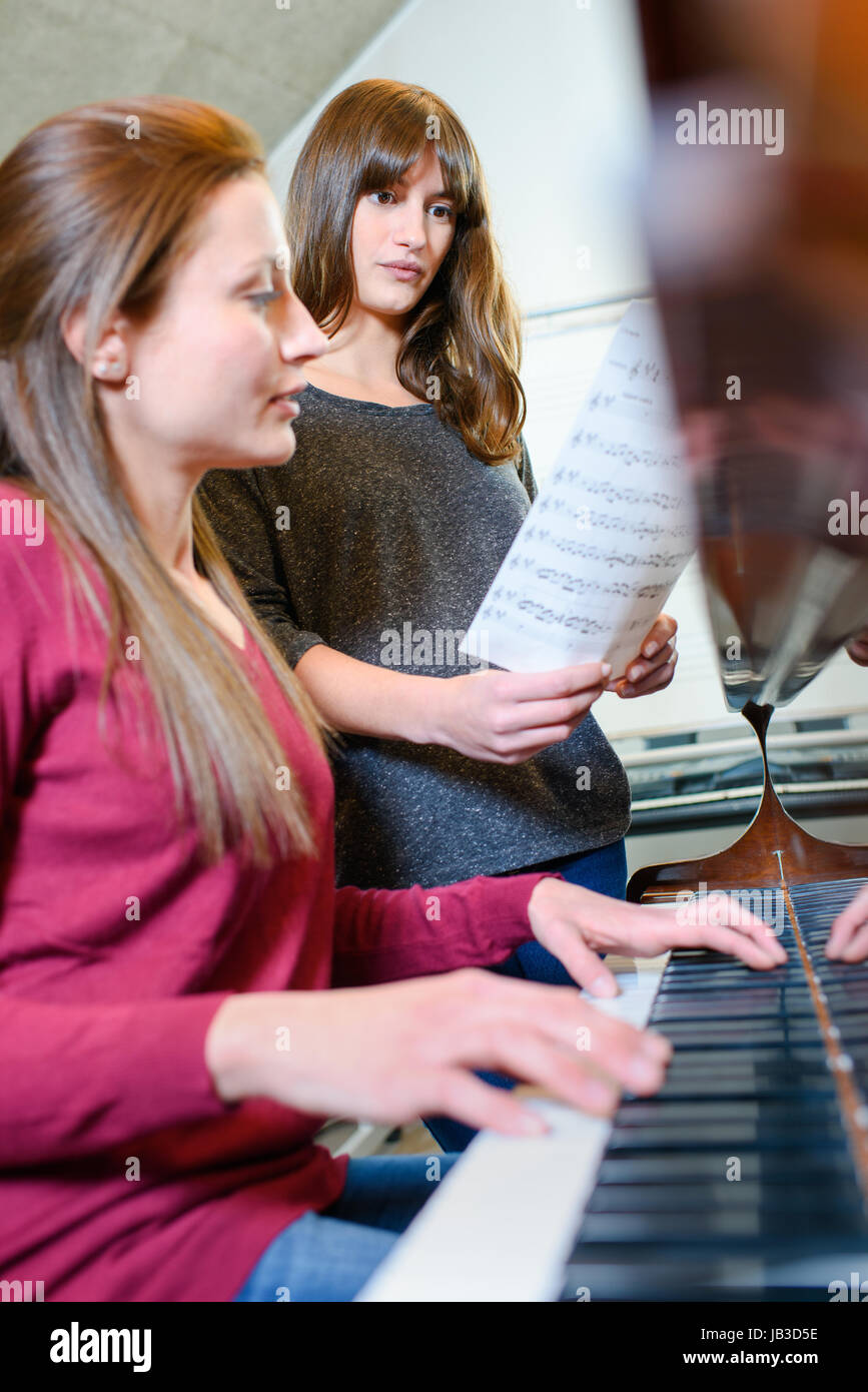 girl ready to sing while friend is playing piano Stock Photo - Alamy