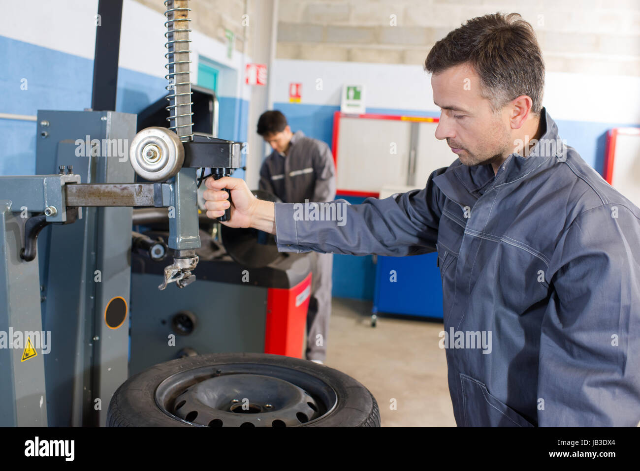 mechanic balancing wheel with machine at garage Stock Photo - Alamy