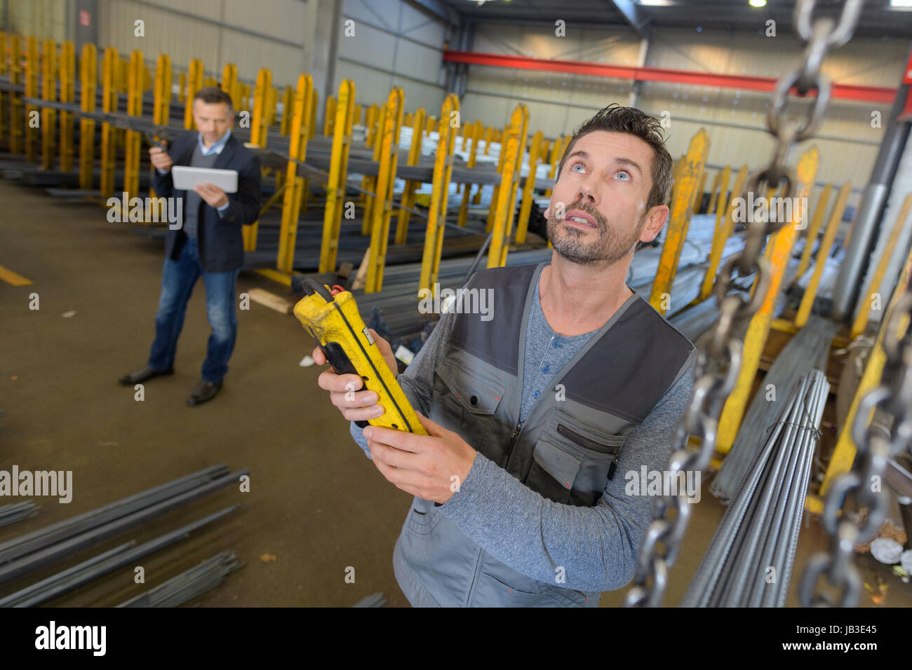 worker looking up in warehouse while holding digital device Stock Photo ...