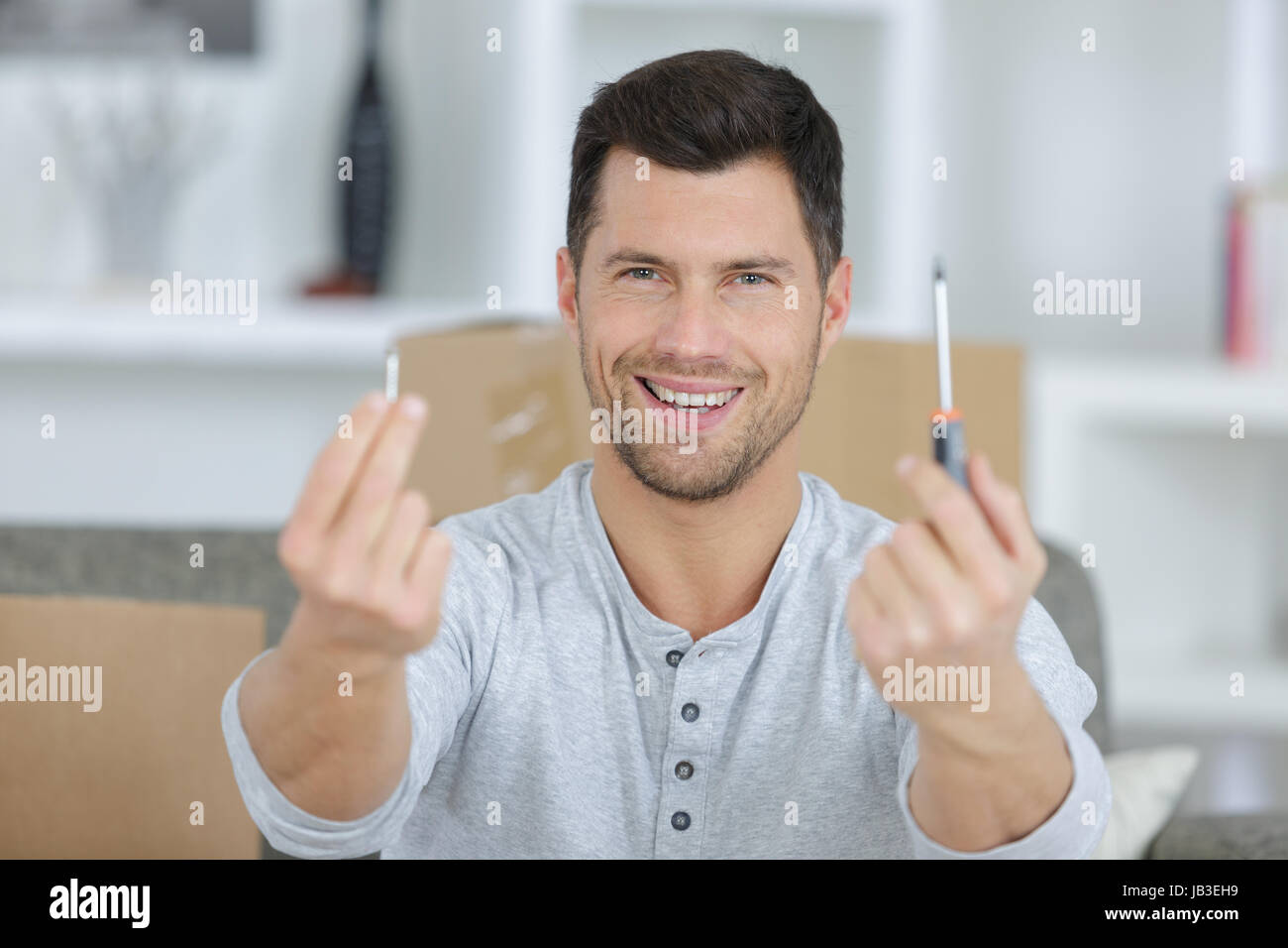 happy man showing a screwdriver and a screw Stock Photo - Alamy