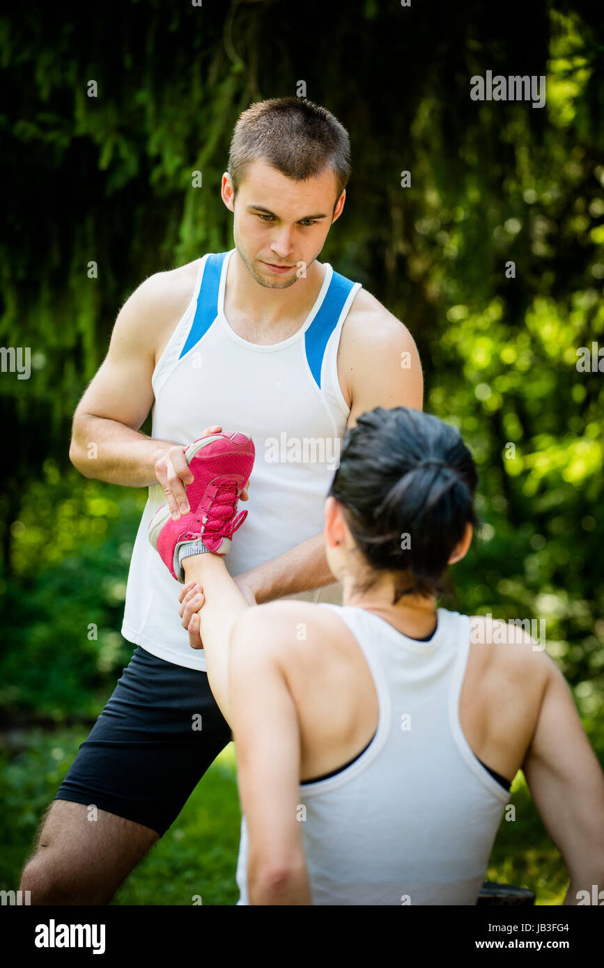 Man helps woman with muscle spasm - stretching her leg Stock Photo - Alamy