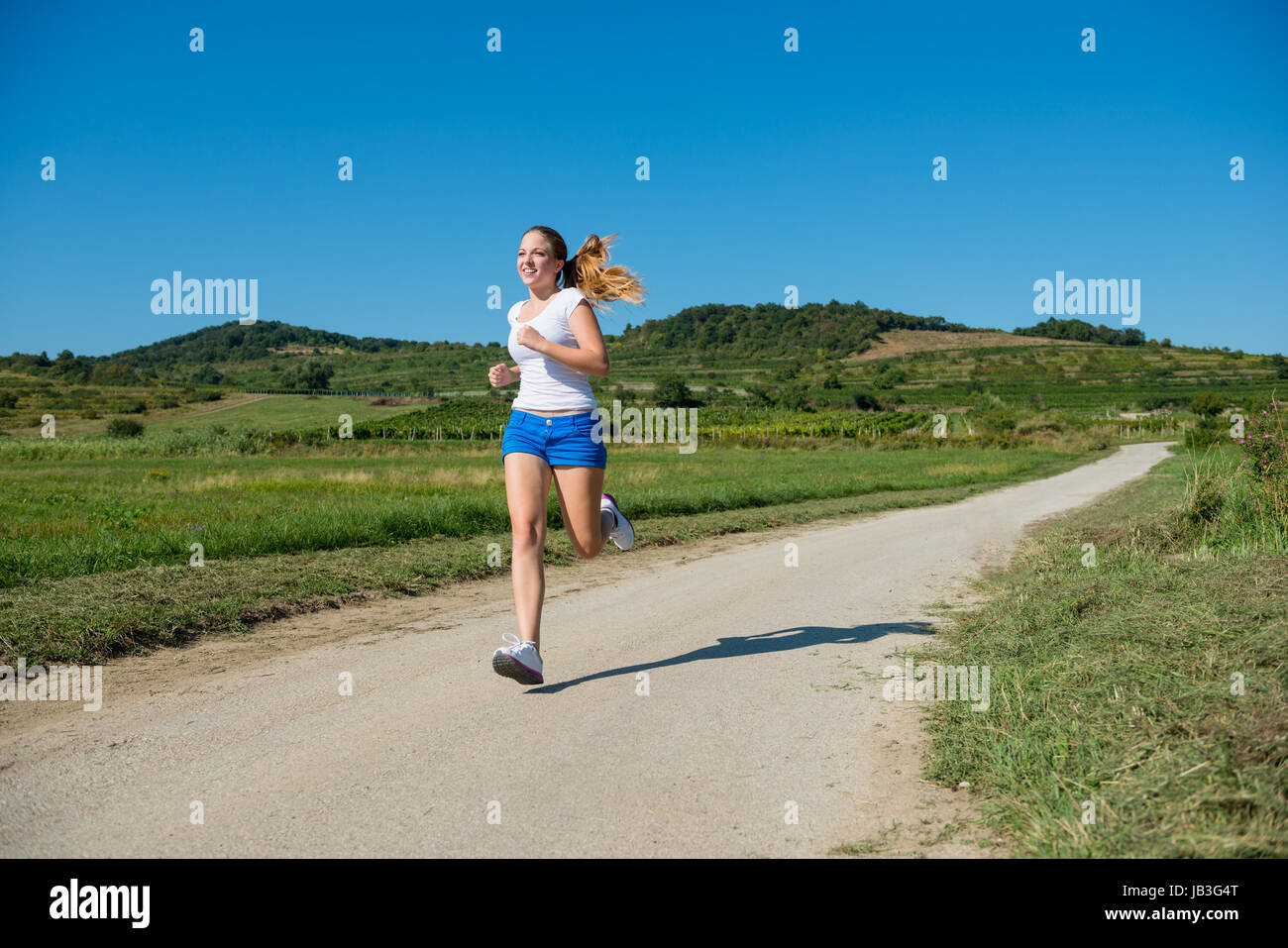 Beautiful teenage girl jogging in nature on sunny day with blue sky ...