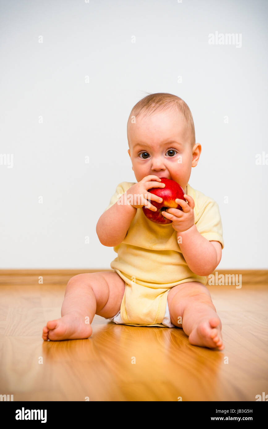 Baby eating apple lying on floor - healthy lifestyle Stock Photo - Alamy