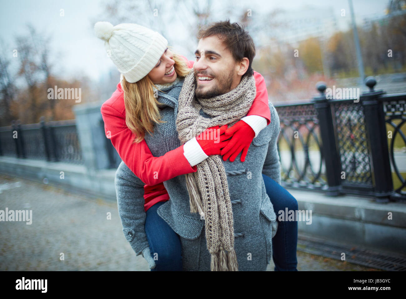 Image of affectionate girl on her boyfriend back in park Stock Photo ...