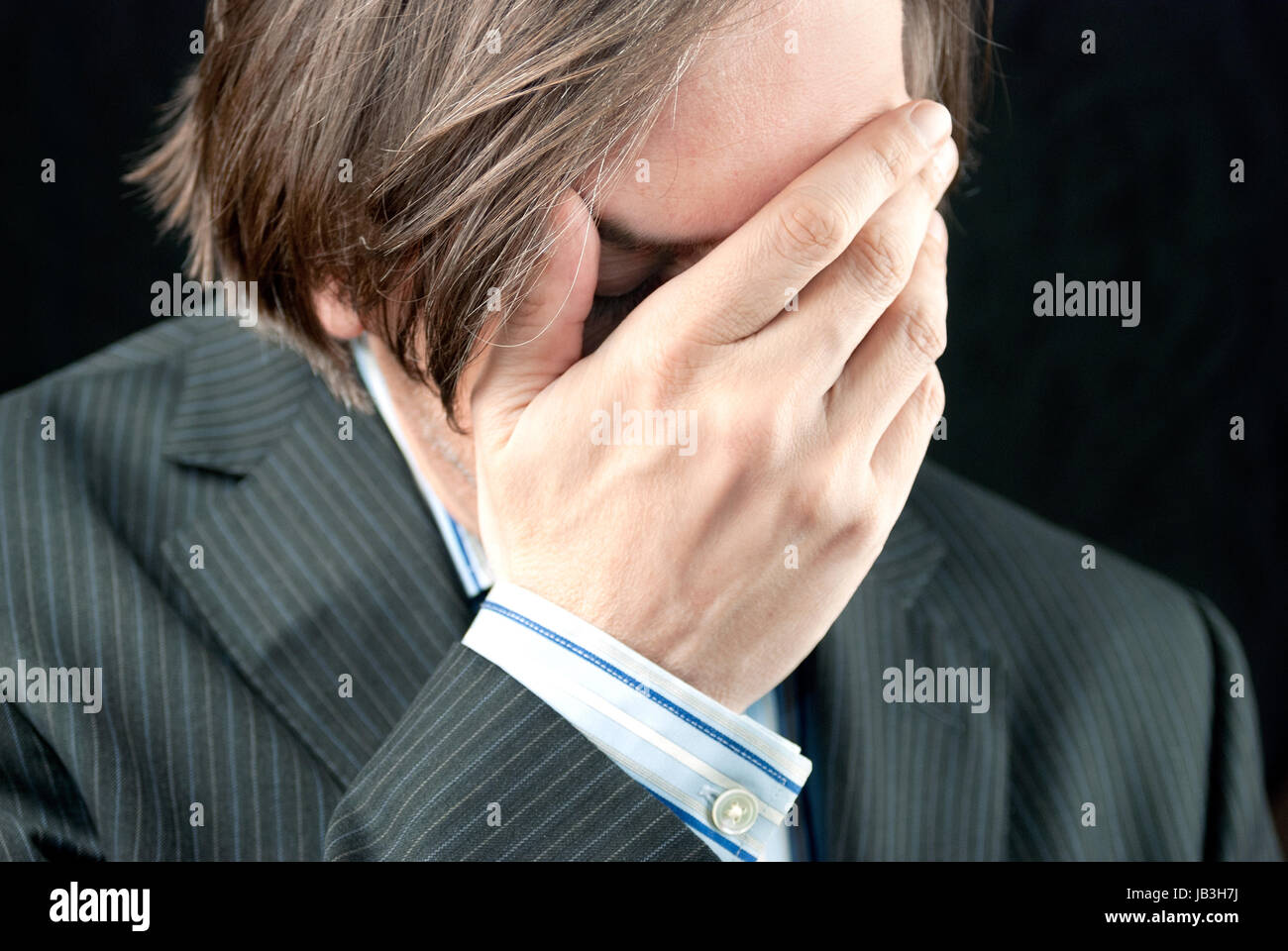Close-up of a businessman holding his head and covering his face with ...