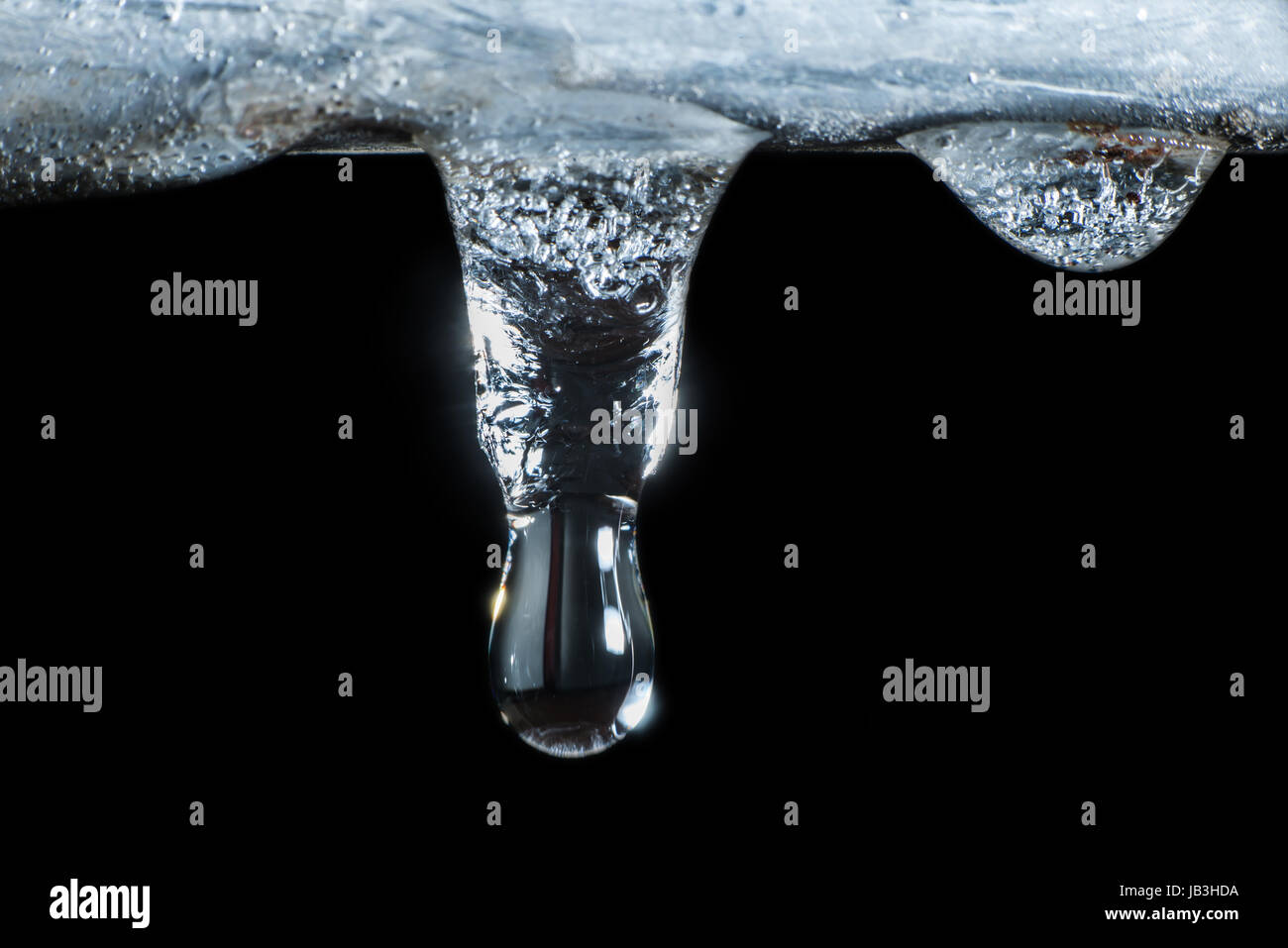 Icicles and drop water. Dark background Stock Photo - Alamy