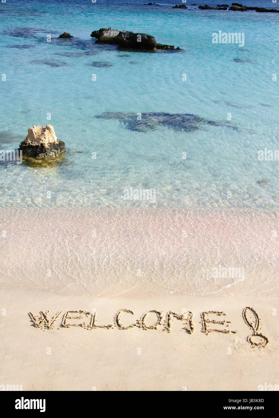 Welcome message written on white sand, with tropical sea waves in ...