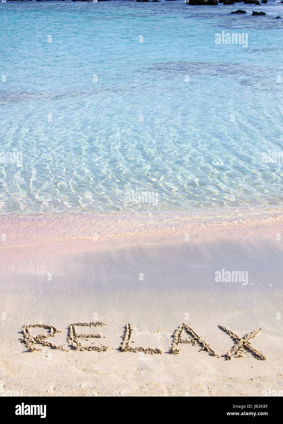 Relax word written in the sand, on a beautiful beach with clear blue ...