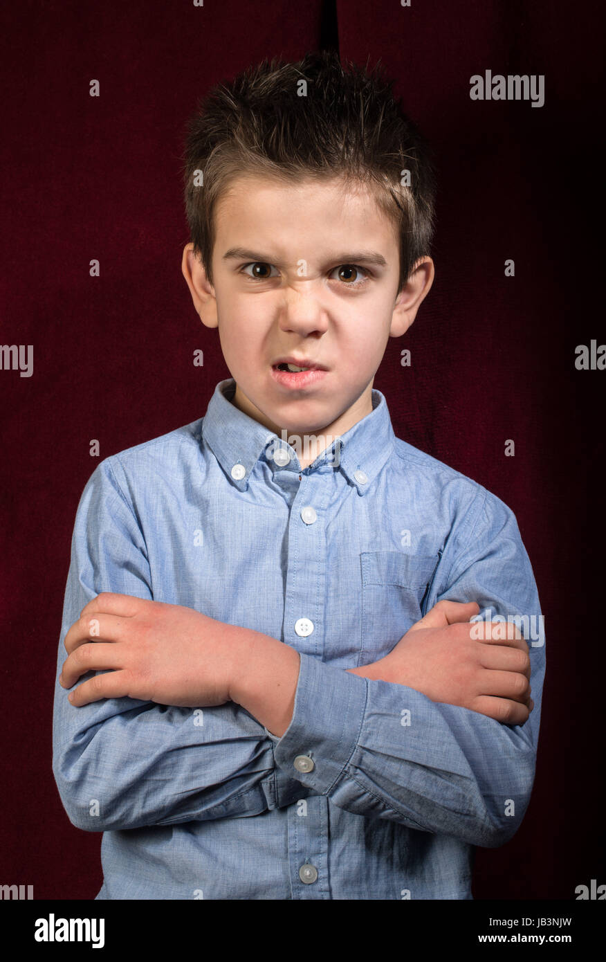 Frowning boy in blue shirt on red background Stock Photo - Alamy