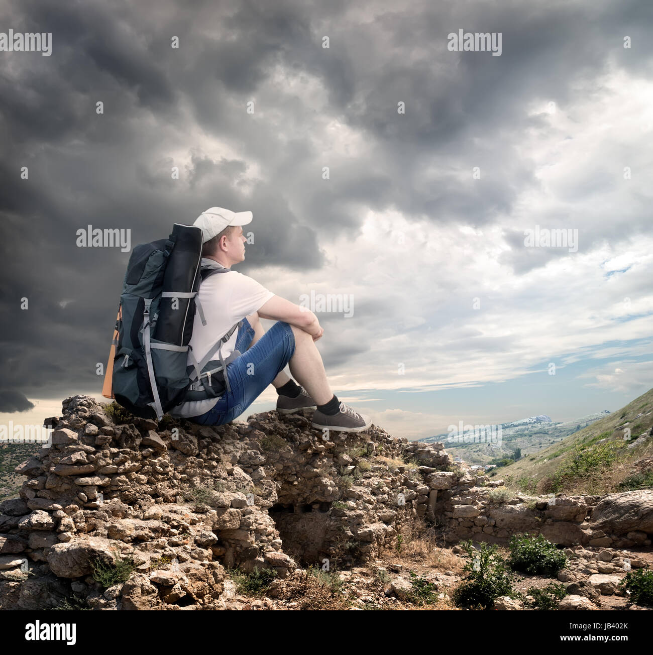 Tourist sitting on the rocks under cloudy sky Stock Photo - Alamy