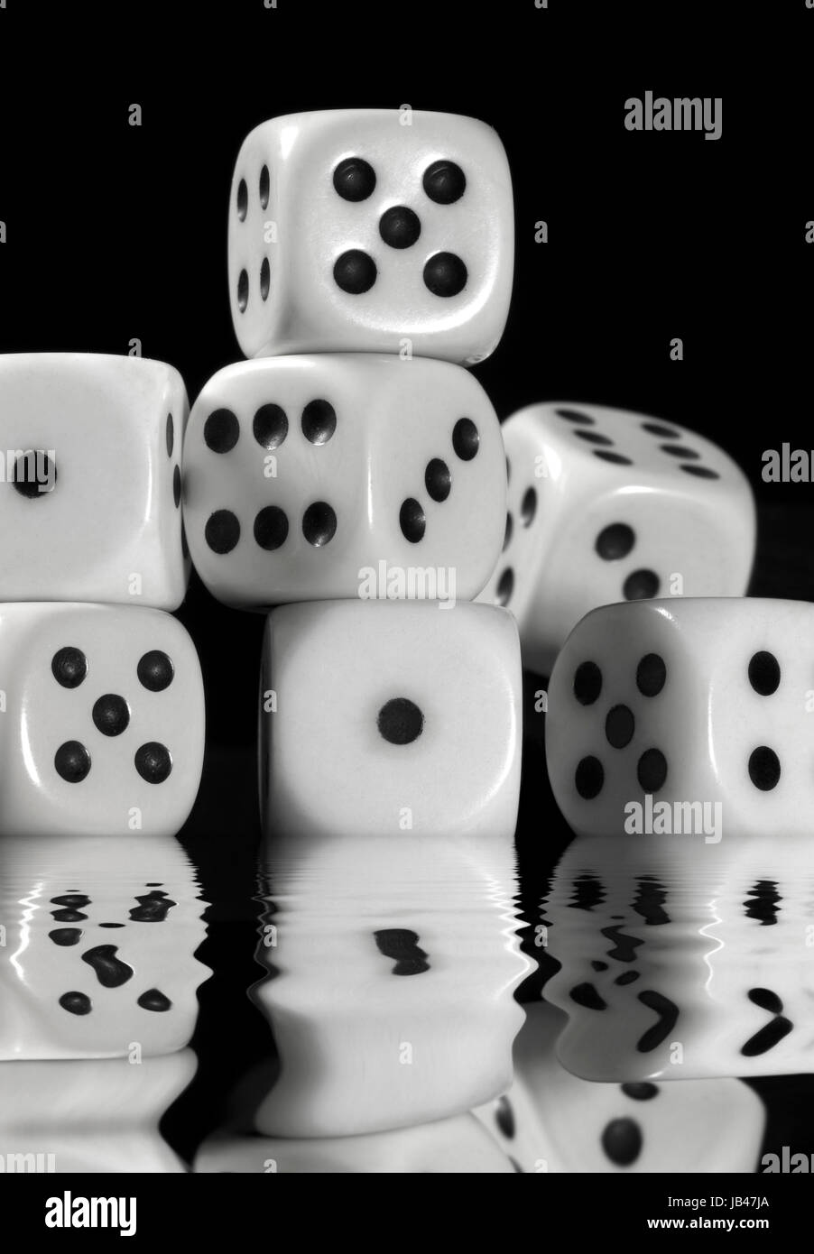 sinking pile of white dice on reflective water surface in black back ...
