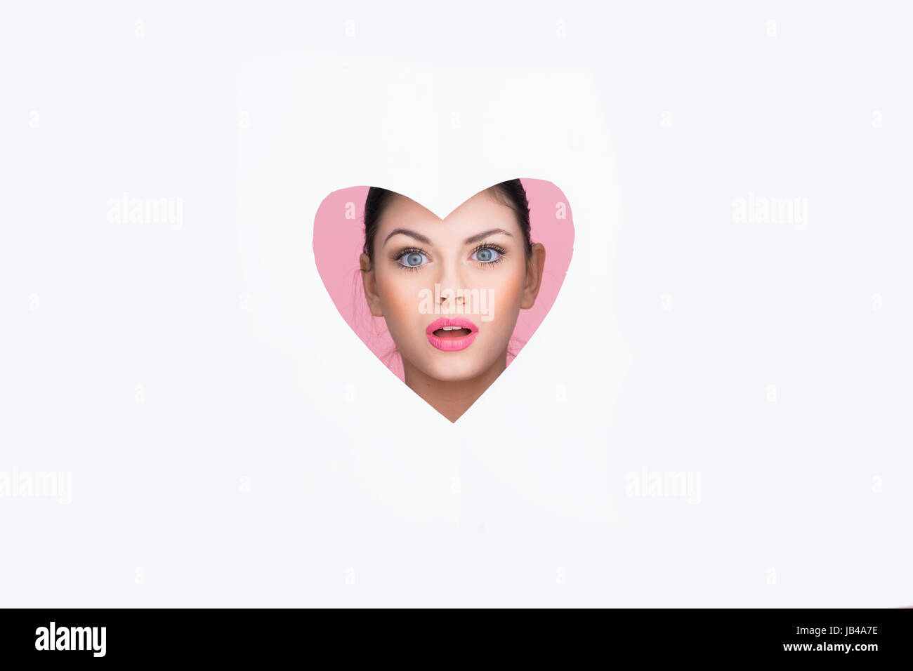 Beautiful woman looking through a heart shaped cutout in a white ...