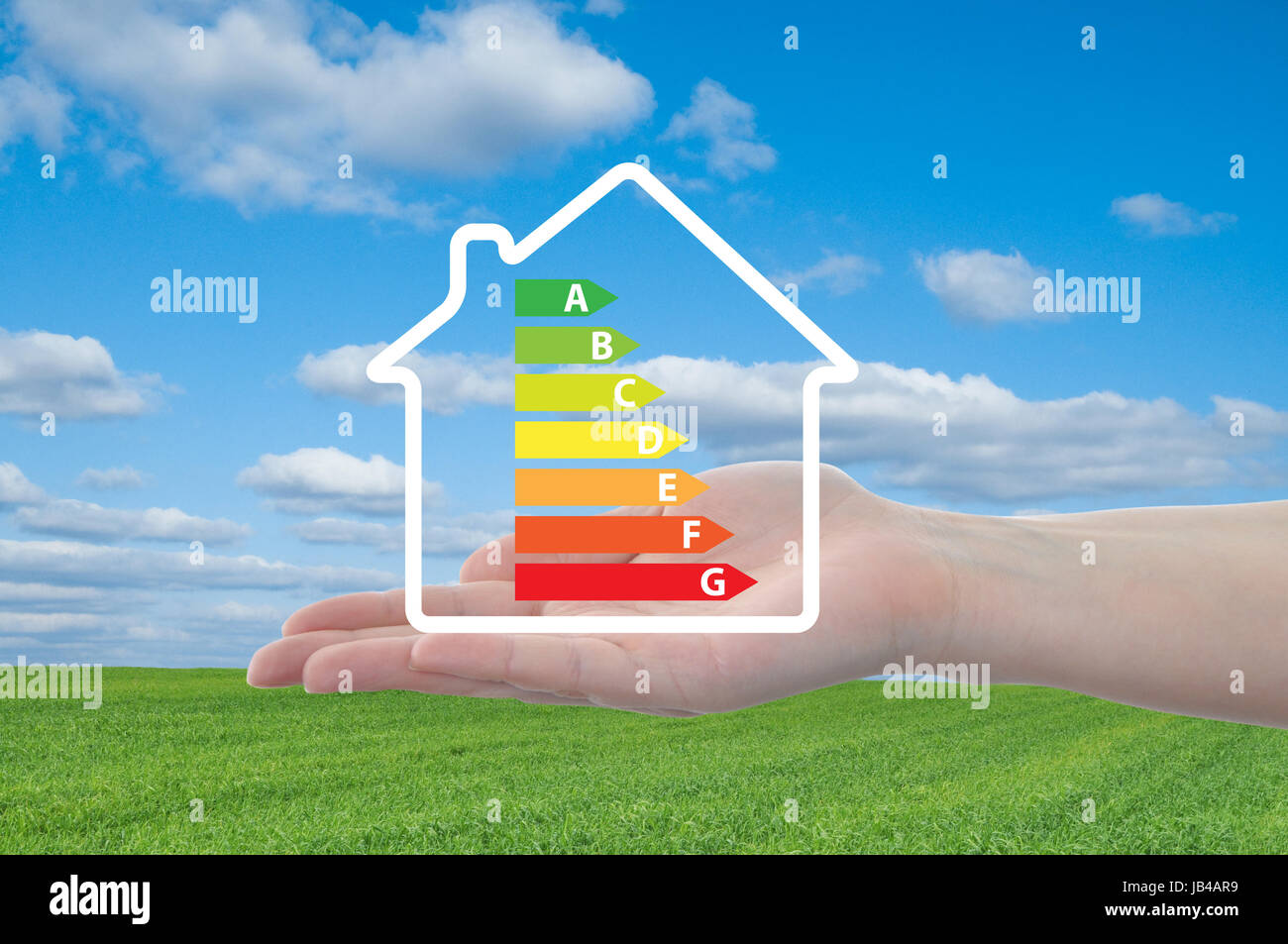 House and energy efficiency graph on hand. Blue sky and meadow in ...