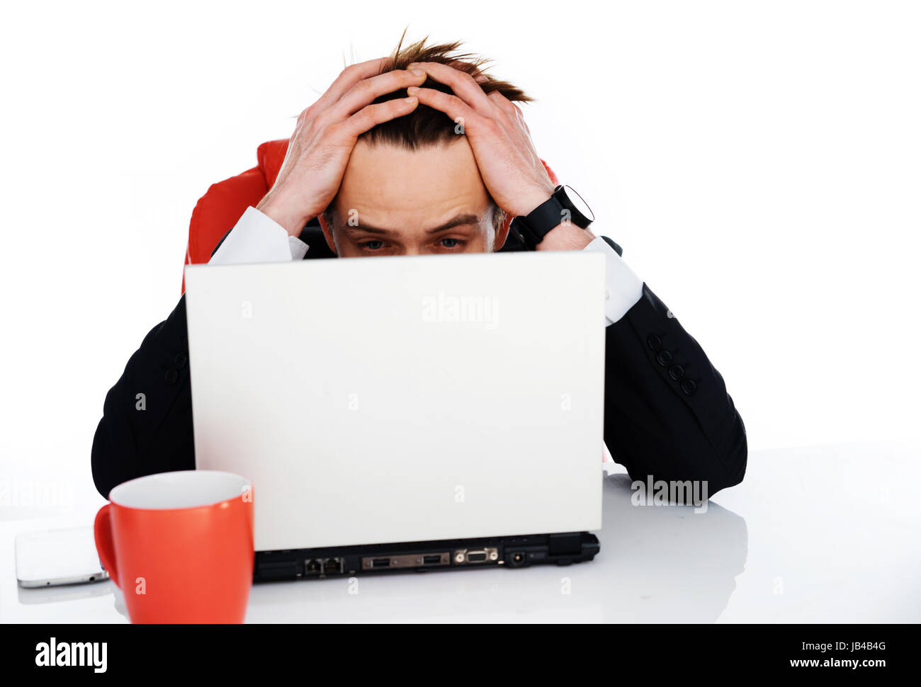 Worried businessman sitting behind his laptop computer holding his head ...