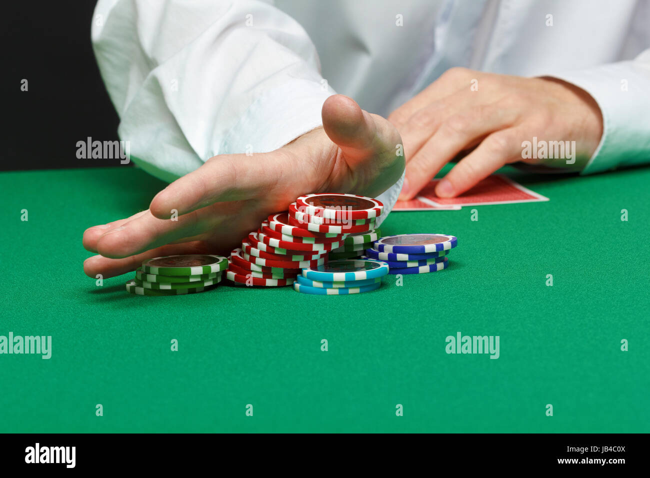 gambler. Male hand with cards and chips on green table Stock Photo - Alamy