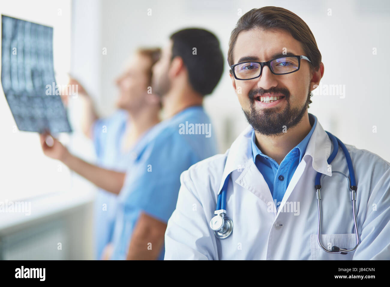 Portrait of friendly doctor looking at camera on background of his ...